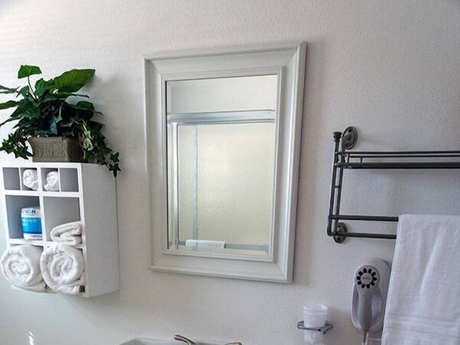 Casa de banho com lavatório assentado, porta-toalhas, prateleira com artigos de higiene e espelho.