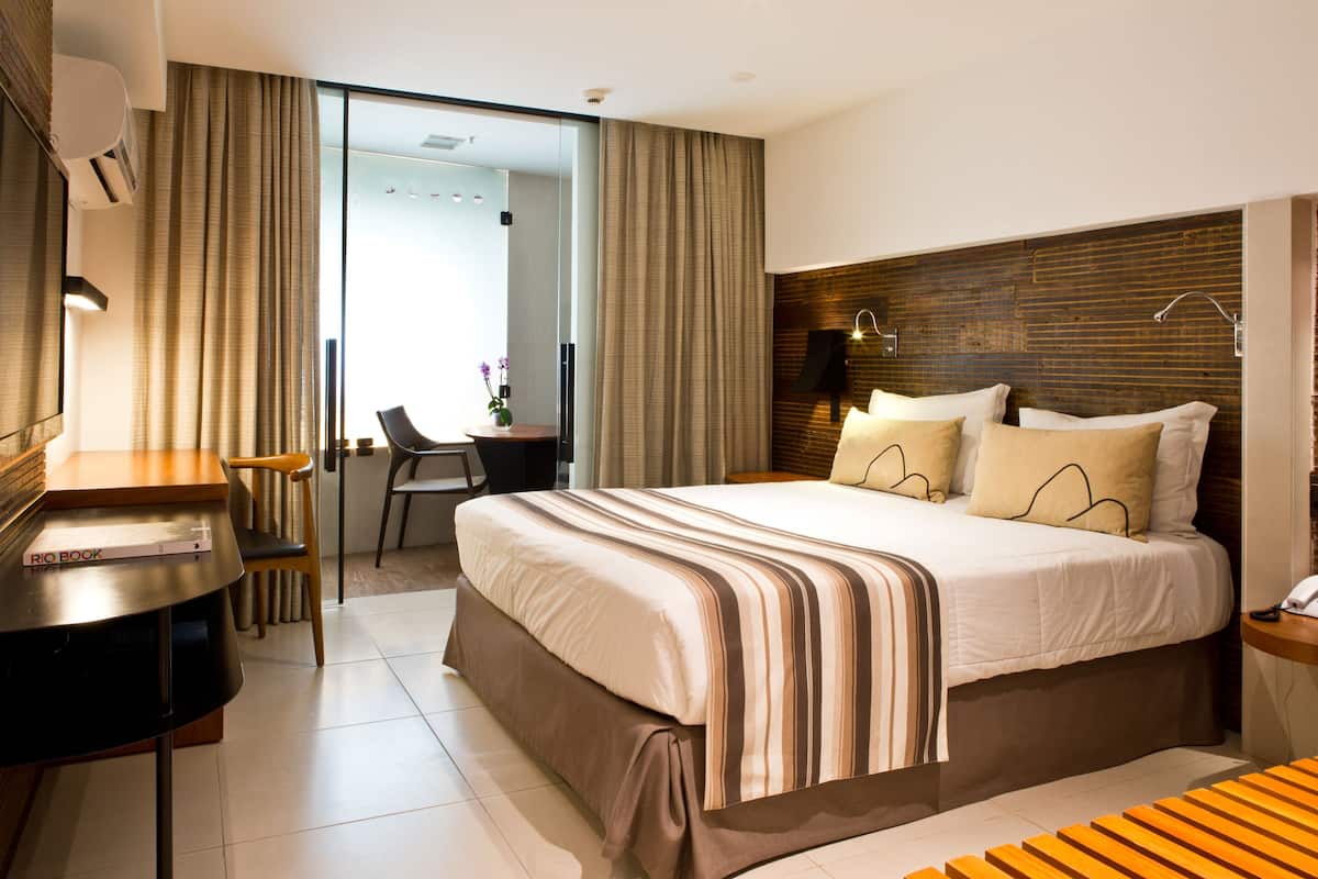 Quarto de hotel moderno com uma cama grande, uma escrivaninha e uma cadeira.