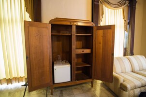 Um armário de madeira com portas abertas, mostrando prateleiras e um pequeno eletrodoméstico branco no interior.