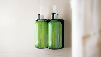Duas garrafas verdes com bombas em uma parede de azulejos brancos.