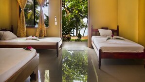 Quarto com duas camas, janela com cortinas e vista para o verde lá fora.