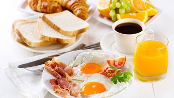 Um prato de café da manhã com ovos, bacon, torrada e um copo de suco de laranja.