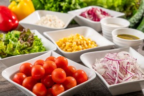 Variedade de vegetais frescos em tigelas, incluindo tomates, milho e cebolas.