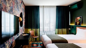 Quarto de hotel com cama, escrivaninha, cadeira, televisão e um letreiro de neon.