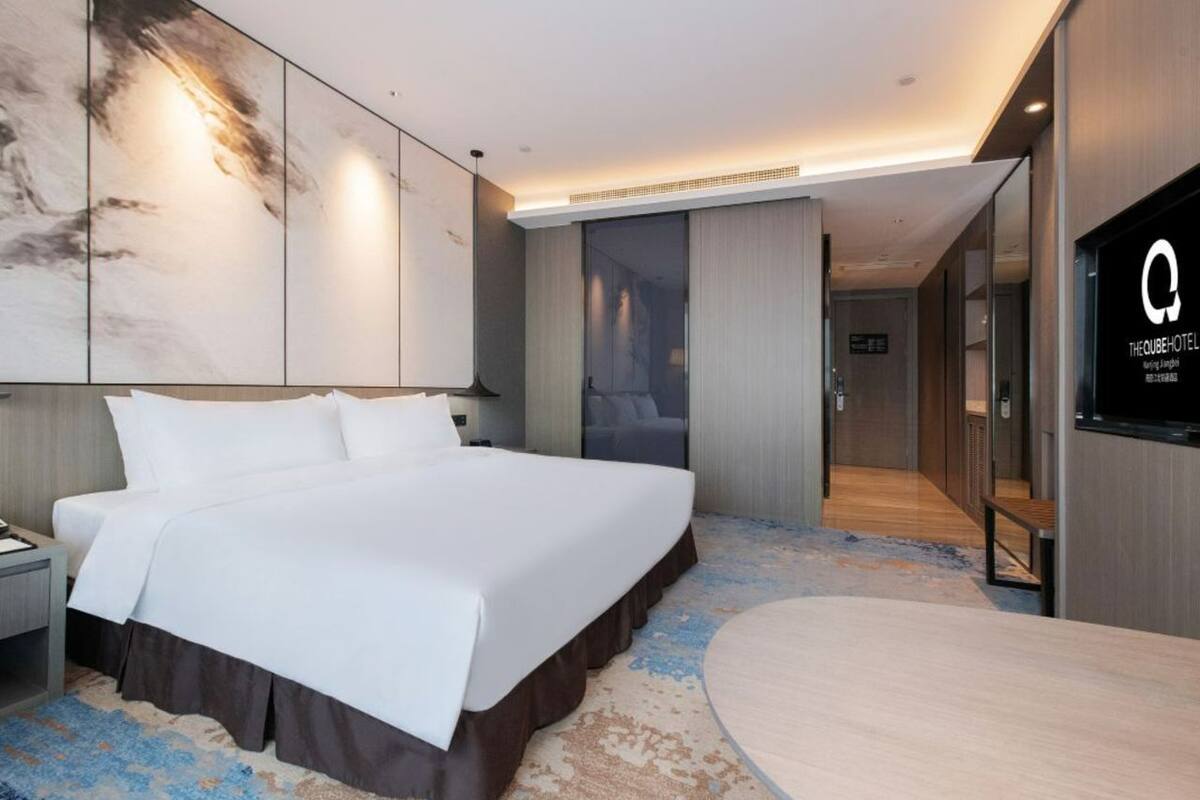 Quarto de hotel moderno com uma cama grande, uma escrivaninha e uma televisão.
