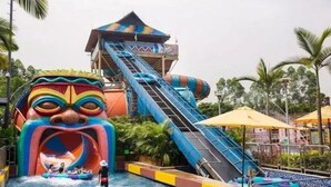 Um parque aquático com um tobogã grande, outro tobogã e uma área de piscina.