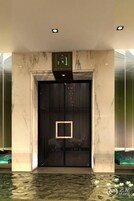 Uma entrada moderna com parede de mármore, painel vertical preto e uma placa sobre a porta.
