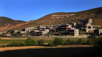 Uma aldeia com edifícios de pedra tradicionais, alguns com detalhes vermelhos, e um céu azul límpido.