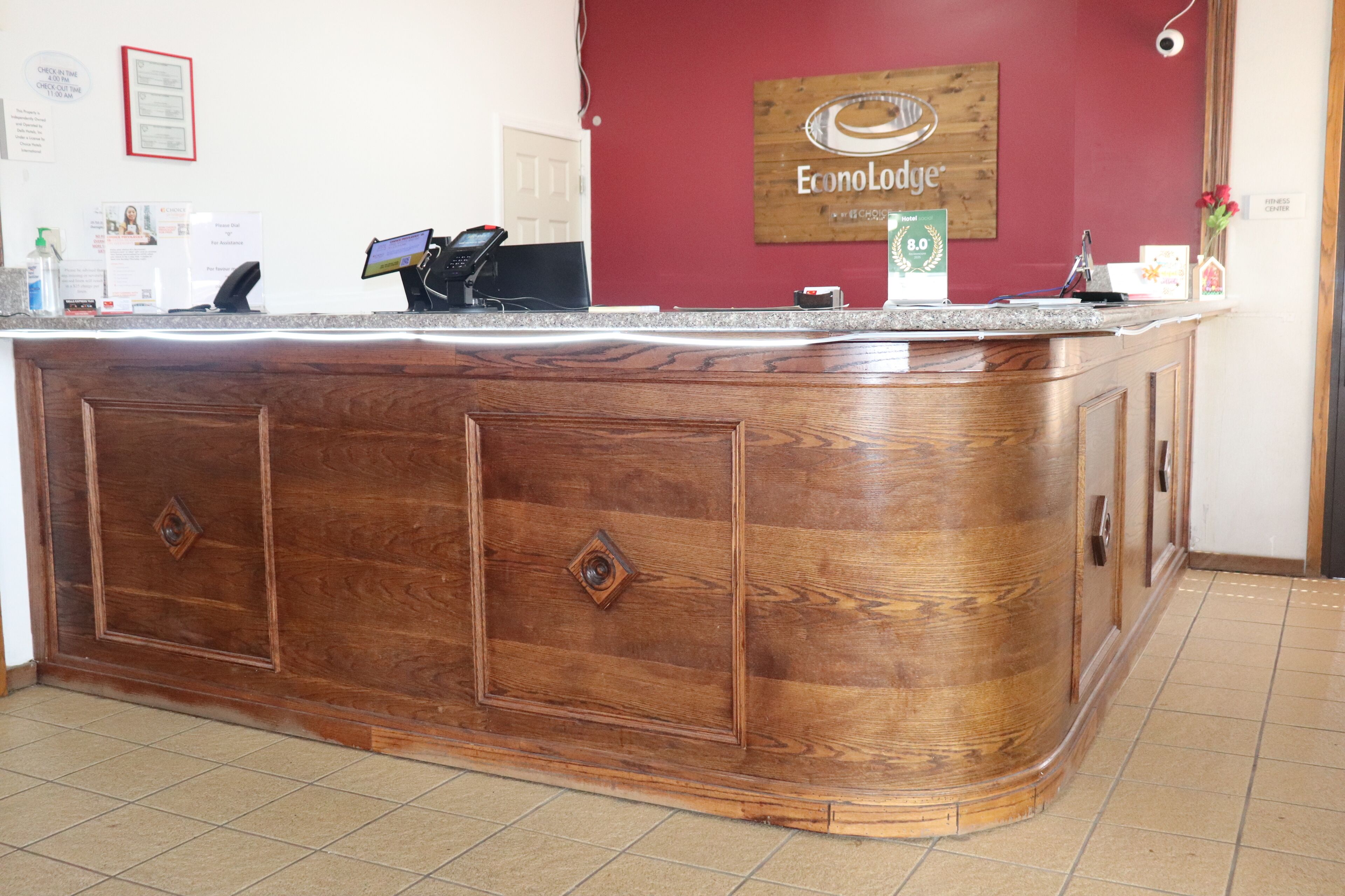 Uma receção com acabamento em madeira, um computador e um sinal a indicar 'Econo Lodge'.