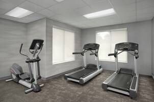 Uma sala de ginástica com esteiras, elíptico e bicicleta ergométrica.