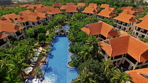 Resort com vários edifícios, uma piscina central e vegetação exuberante.