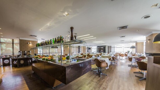 Um amplo hall de hotel com área de bar central, diversos arranjos de assentos e design moderno.