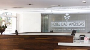 Balcão de recepção de hotel com uma placa indicando "HOTEL DAS AMÉRICAS" e um logotipo acima.