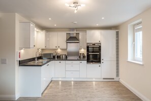 Uma cozinha moderna com armários brancos, eletrodomésticos de aço inoxidável e uma ilha central com pia.