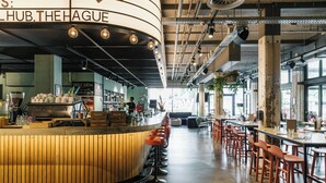 Uma área de bar moderna com balcão curvo, banquetas e um quadro de cardápio.
