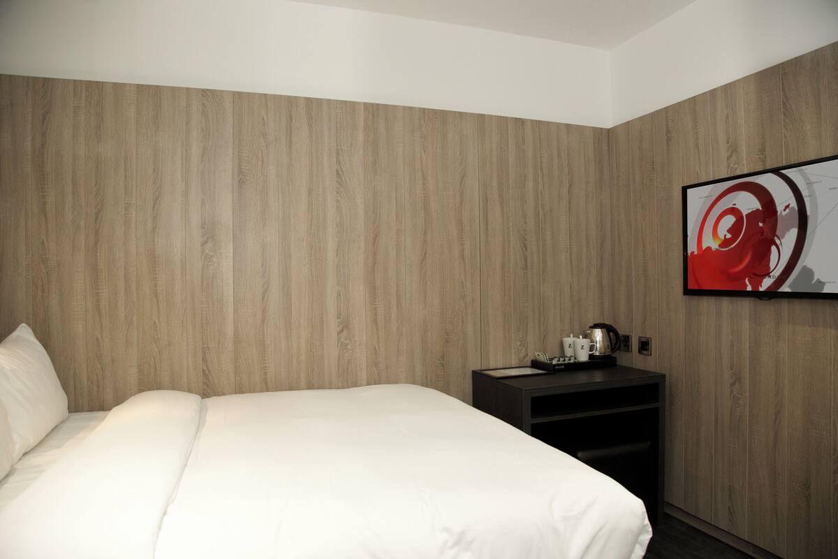 Quarto de hotel com uma cama grande, mesa de cabeceira e uma obra de arte pendurada na parede.
