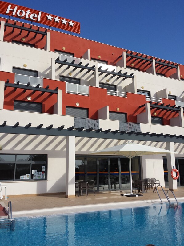 Hotel com piscina, área de estar externa e placa indicando três estrelas.