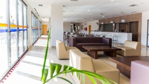 Um hall de hotel moderno com área de estar, balcão de recepção e vista para o exterior.