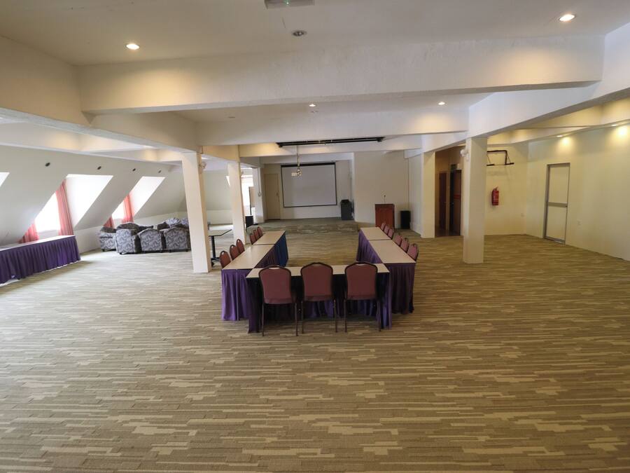 Uma sala de conferências com uma mesa comprida e cadeiras, tetos altos e janelas grandes.