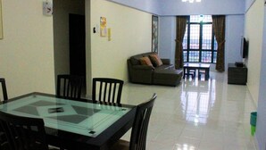 Uma sala de estar espaçosa com uma mesa de jantar de vidro, um sofá e um ventilador de teto.