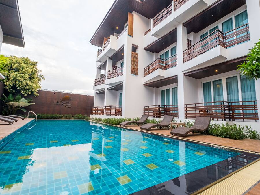 Um hotel moderno com piscina, várias varandas e espreguiçadeiras.