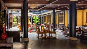 Um interior tradicional com mobiliário de madeira, colunas e elementos decorativos.