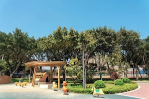 Um parque com um pavilhão de madeira, bancos e um parquinho.