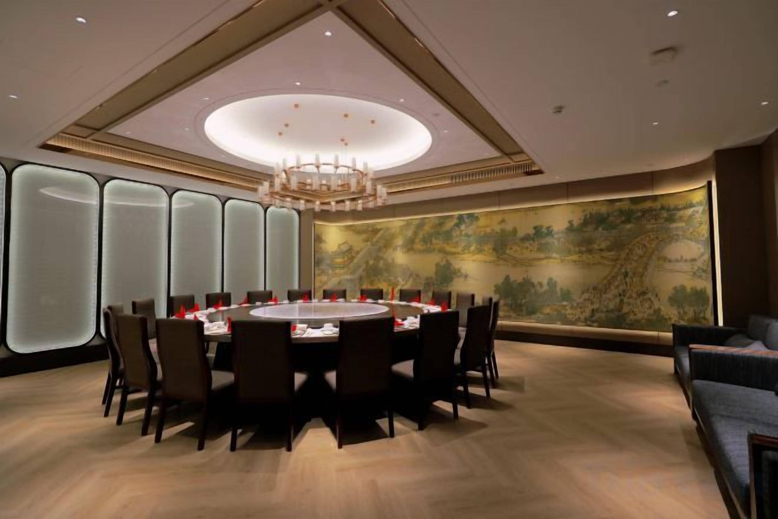 Uma sala de conferências com uma mesa redonda, cadeiras e um lustre.