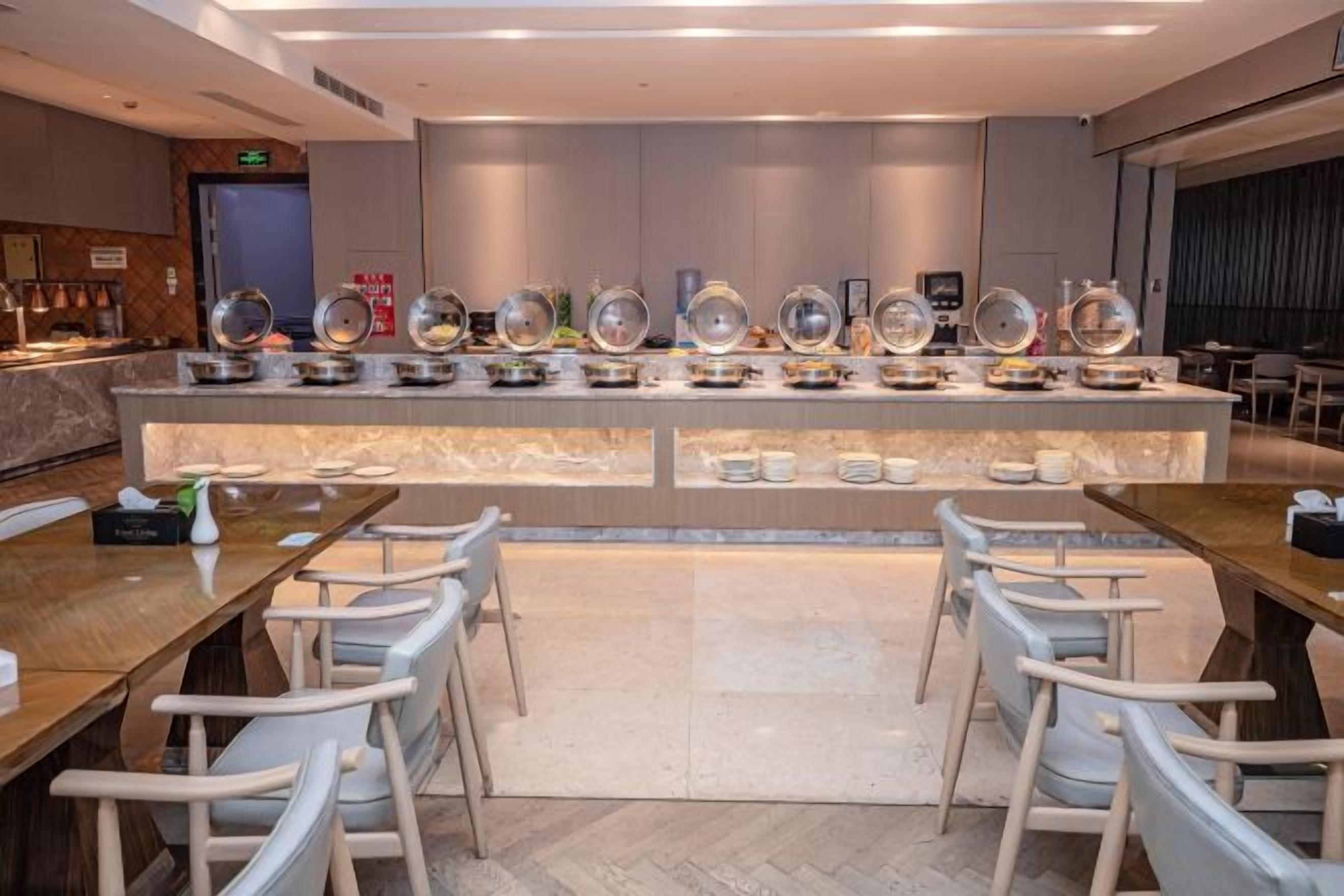 Um restaurante moderno com um balcão extenso, diversas áreas de estar e uma variedade de pratos à mostra.