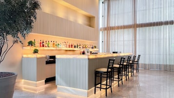 Uma área de bar moderna com um balcão comprido, vários bancos e uma variedade de garrafas de bebidas.