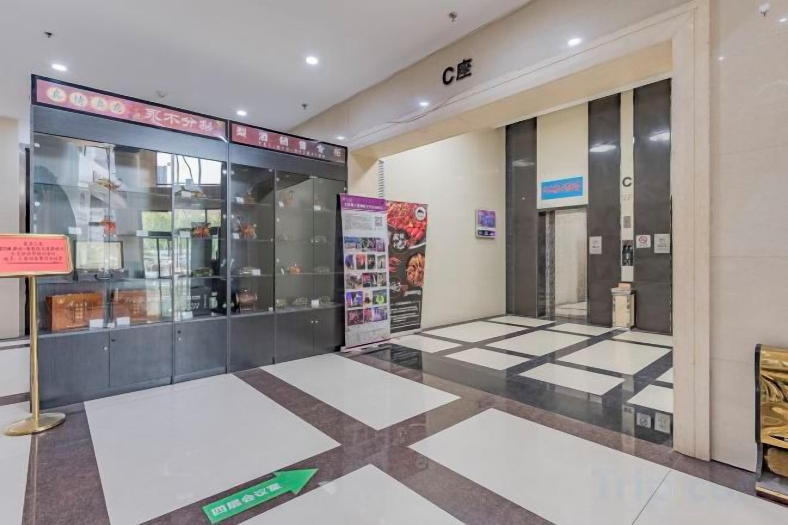 Um hall de hotel com um balcão de recepção, uma vitrine de vidro e uma placa de sinalização.