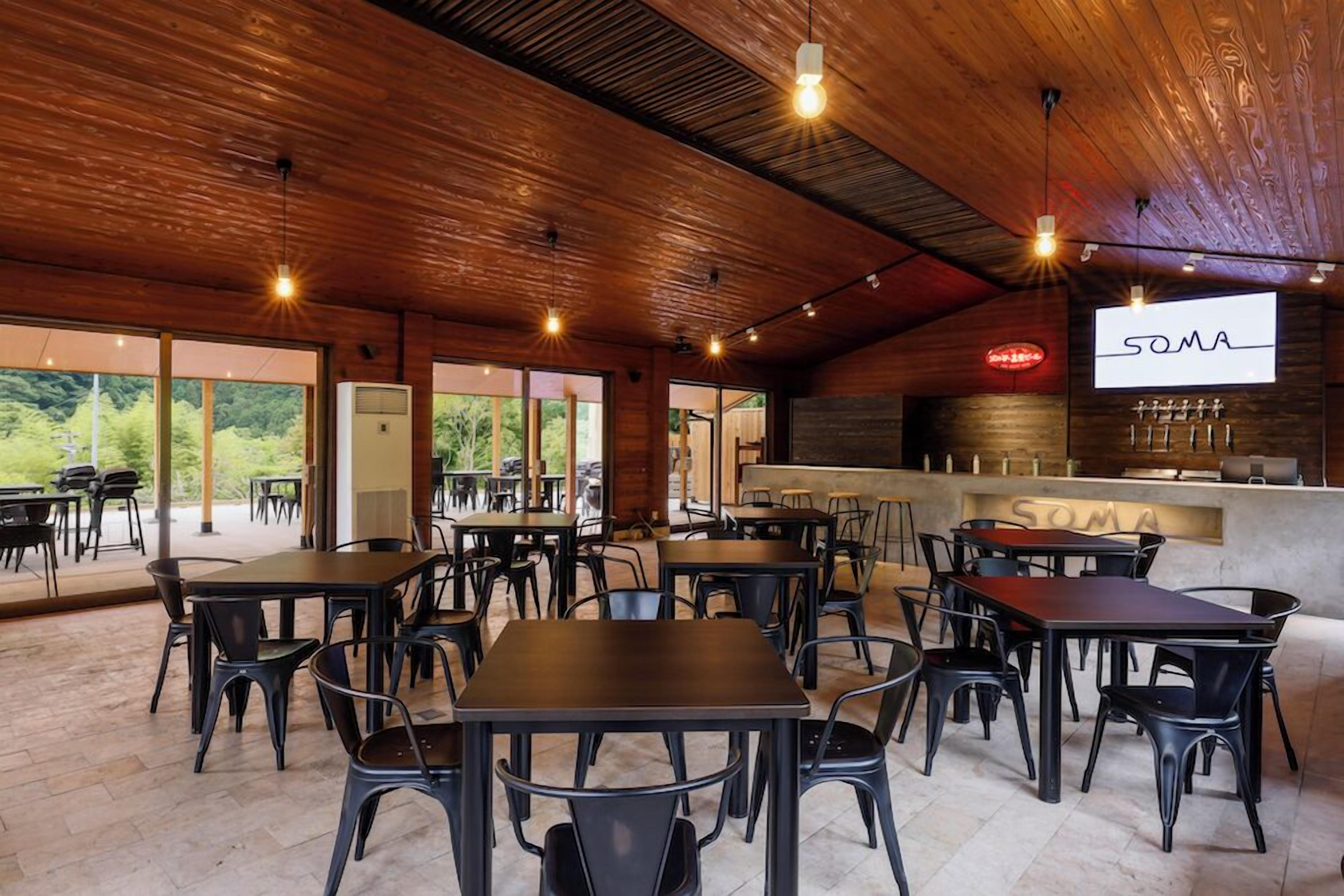 Restaurante com teto e mesas de madeira, além de cadeiras.