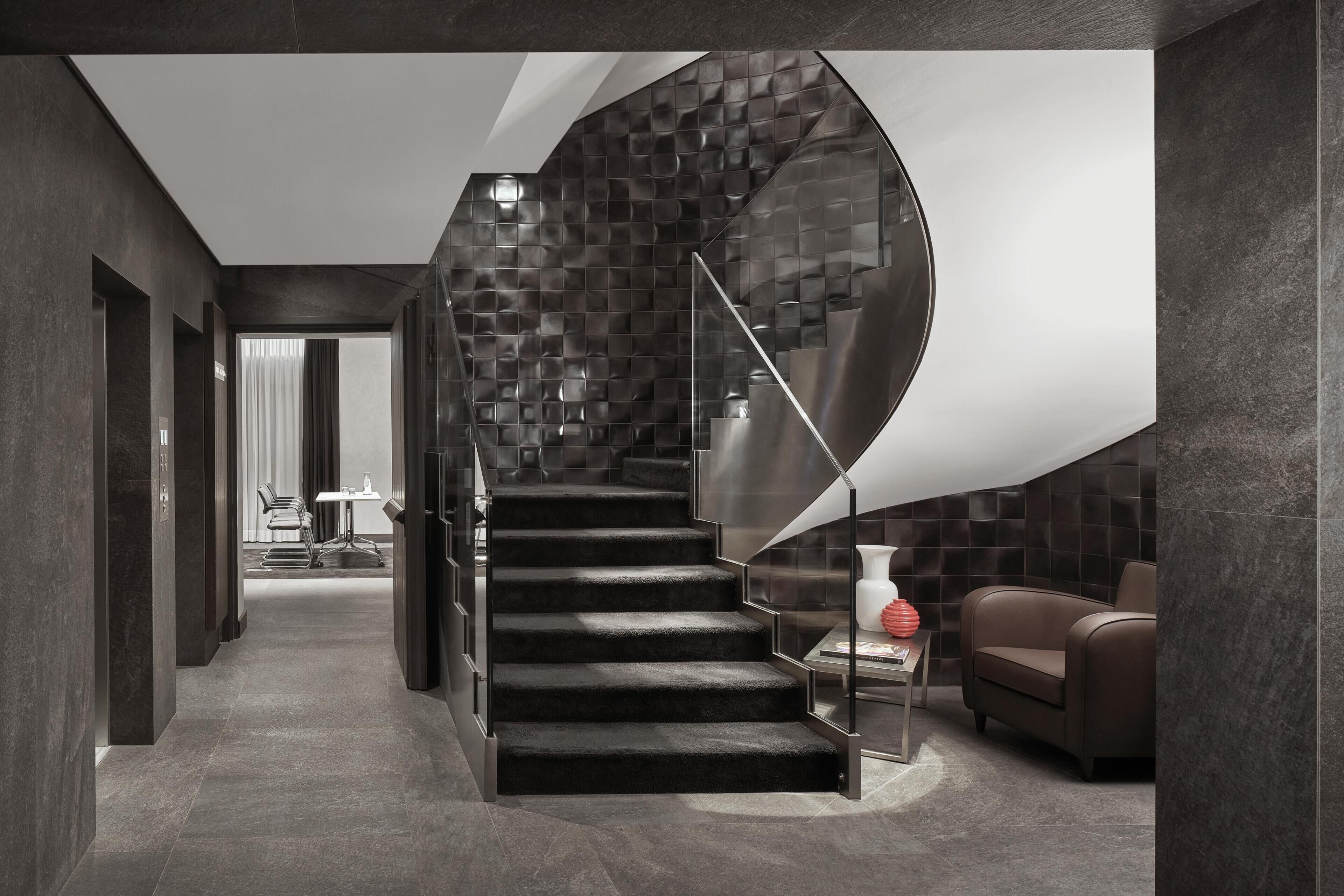 Um interior moderno com escada em espiral, paredes escuras e design minimalista.