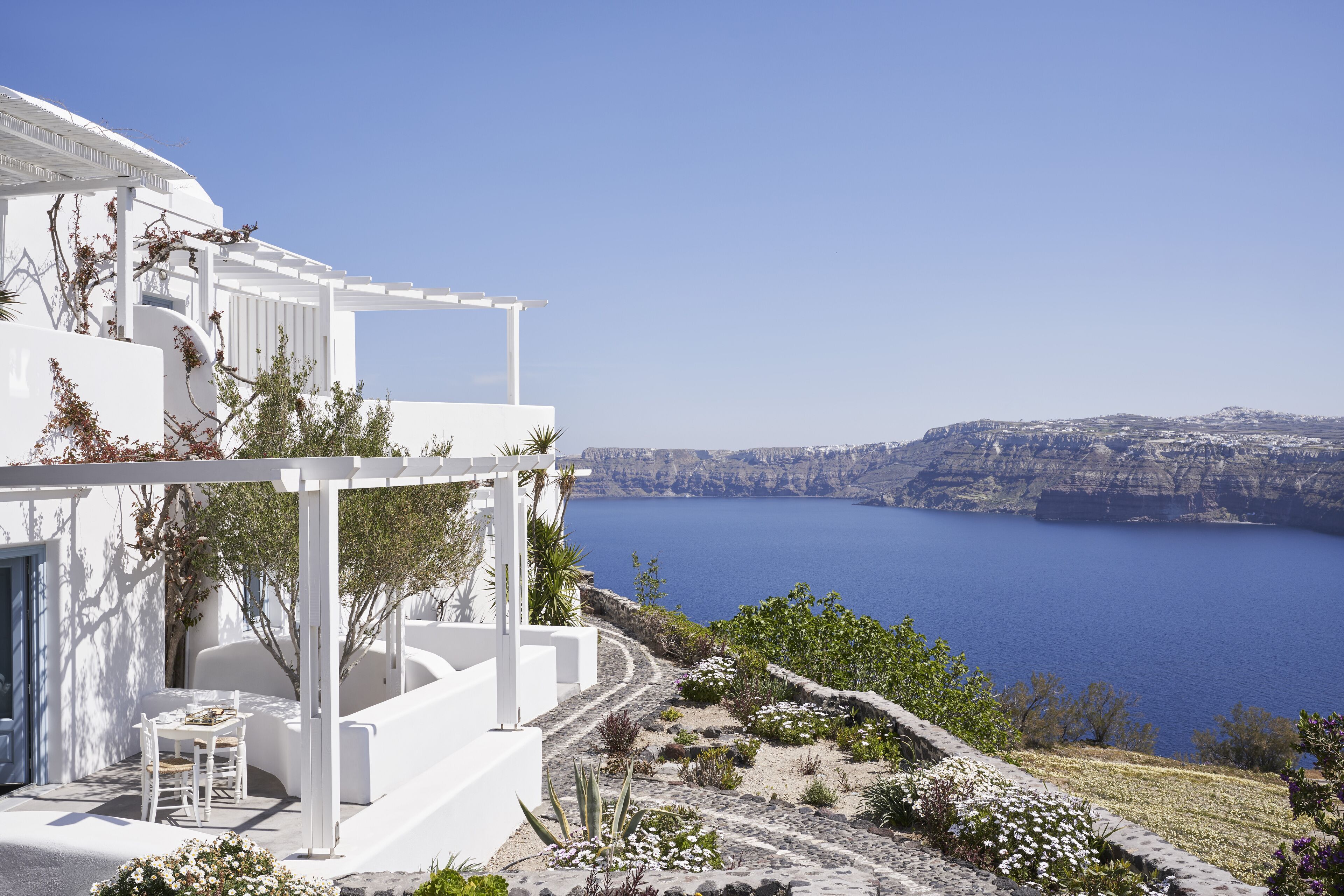 Um edifício branco com terraço que oferece vista para a água e falésias.