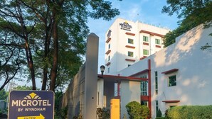 Entrada de hotel com placa indicando 'MICROTEL BY WYNDHAM' e uma seta apontando para o edifício.
