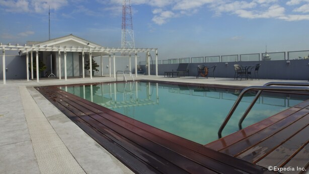 Piscina com deck de madeira, área de estar coberta e vista para uma torre de comunicação.