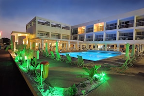 Um hotel moderno com piscina, várias varandas e áreas de estar ao ar livre.