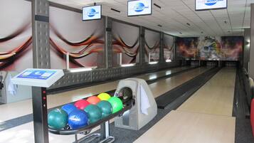 Uma pista de boliche com várias pistas, uma máquina devolvedora de bolas e painéis suspensos exibindo o logotipo Euro Bowling.
