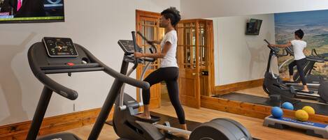 Uma academia com esteiras, espelho e bolas de exercício.
