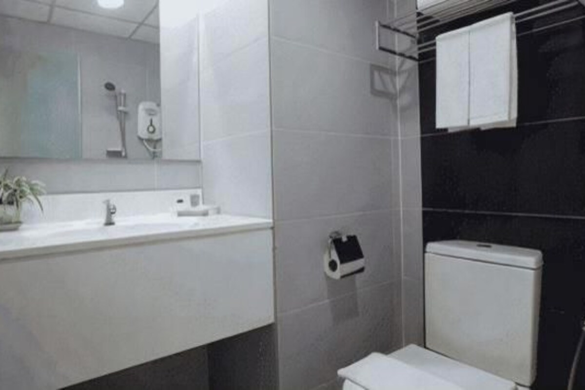 Casa de banho com lavatório branco, espelho e sanita.