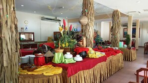 Disposição de buffet com diversos alimentos e decorações, incluindo uma grande peça central com plantas e elementos tradicionais.