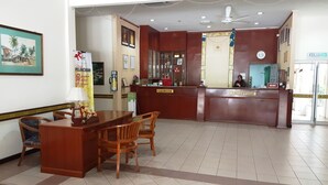 Uma área de recepção com uma mesa de madeira, cadeiras, balcão e um relógio.
