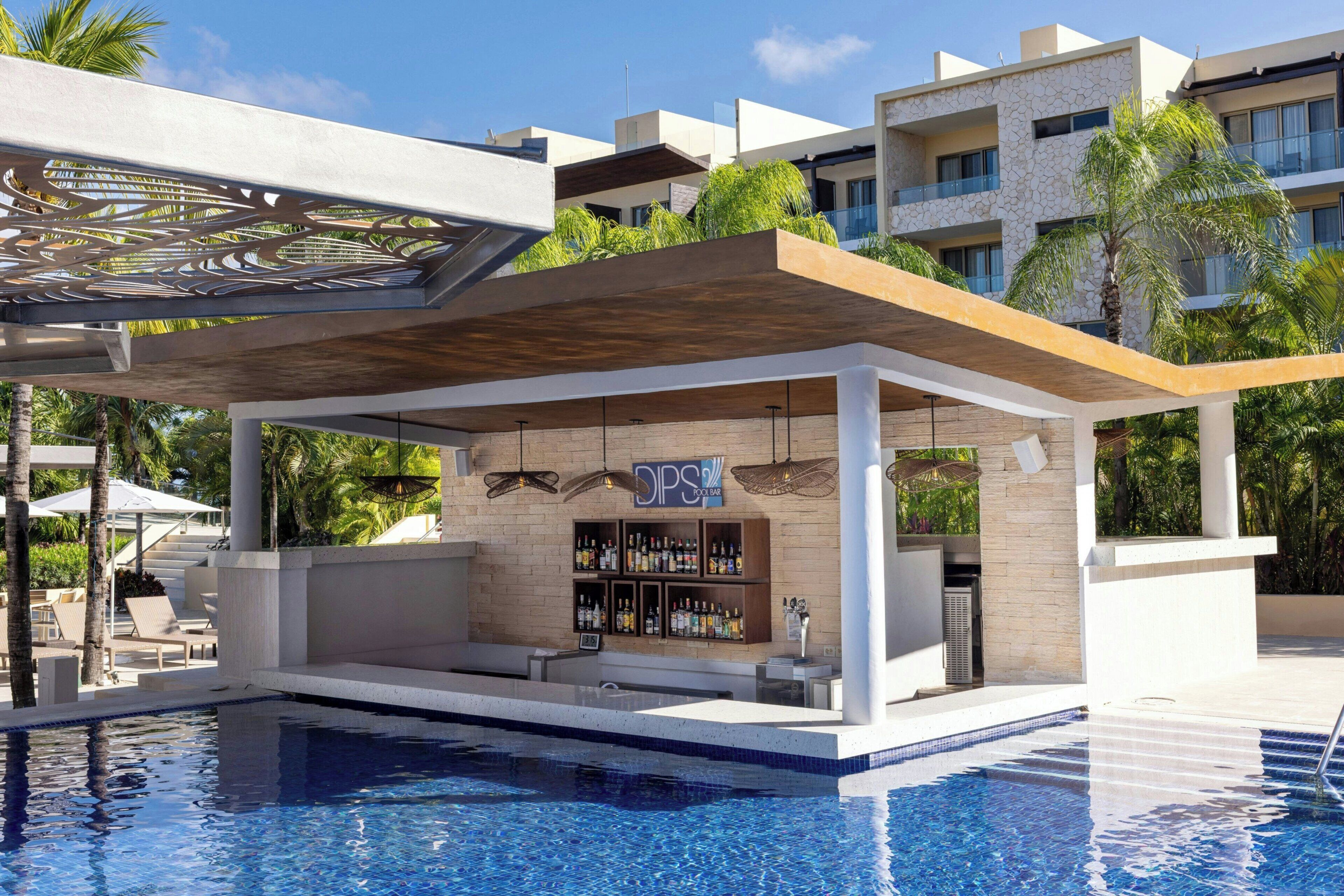 Um bar junto à piscina, com balcão, área de estar e placa com o dizeres 'OPS Bar'.