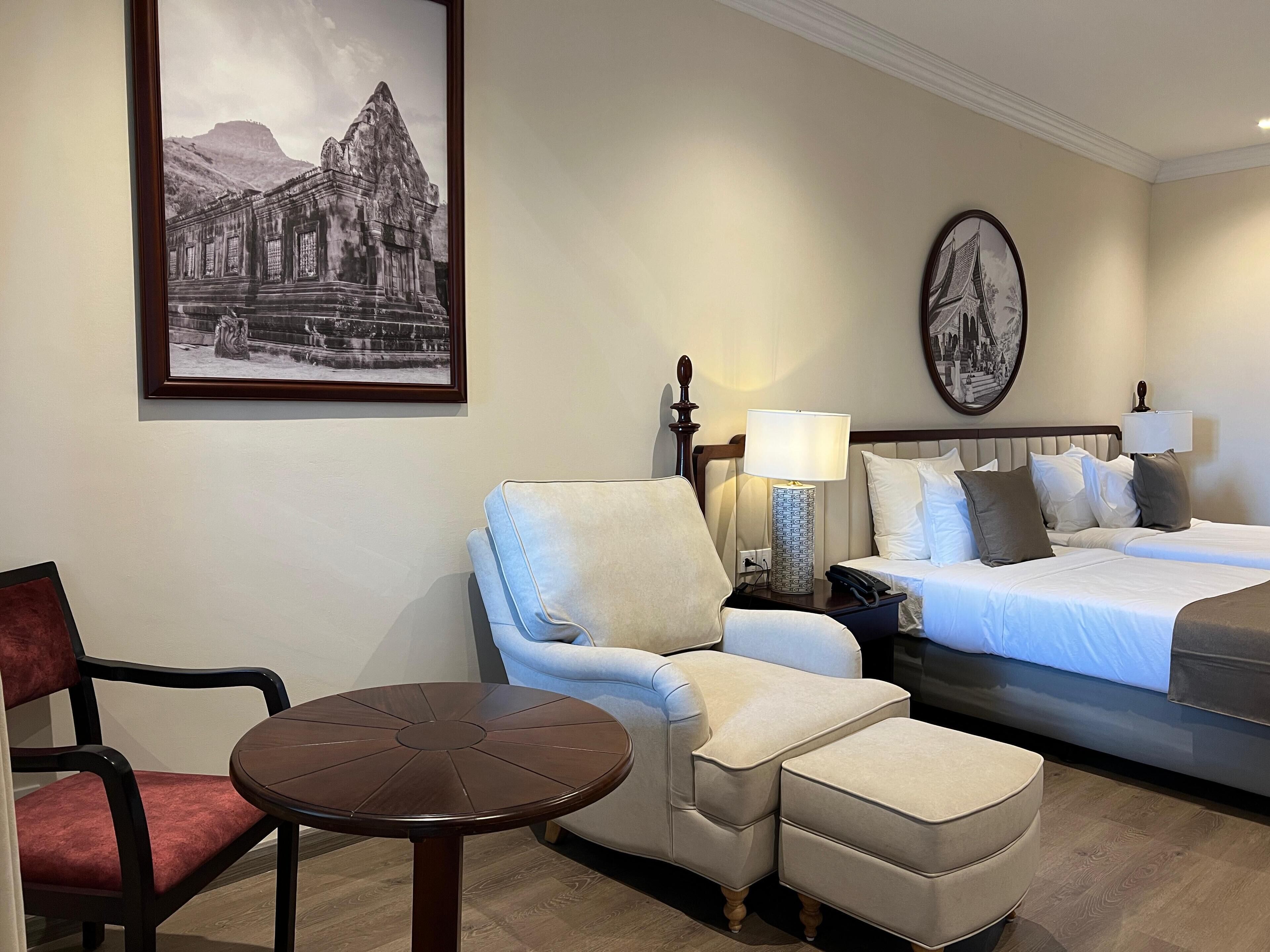 Quarto de hotel com uma cama, uma cadeira, uma mesa e um abajur.