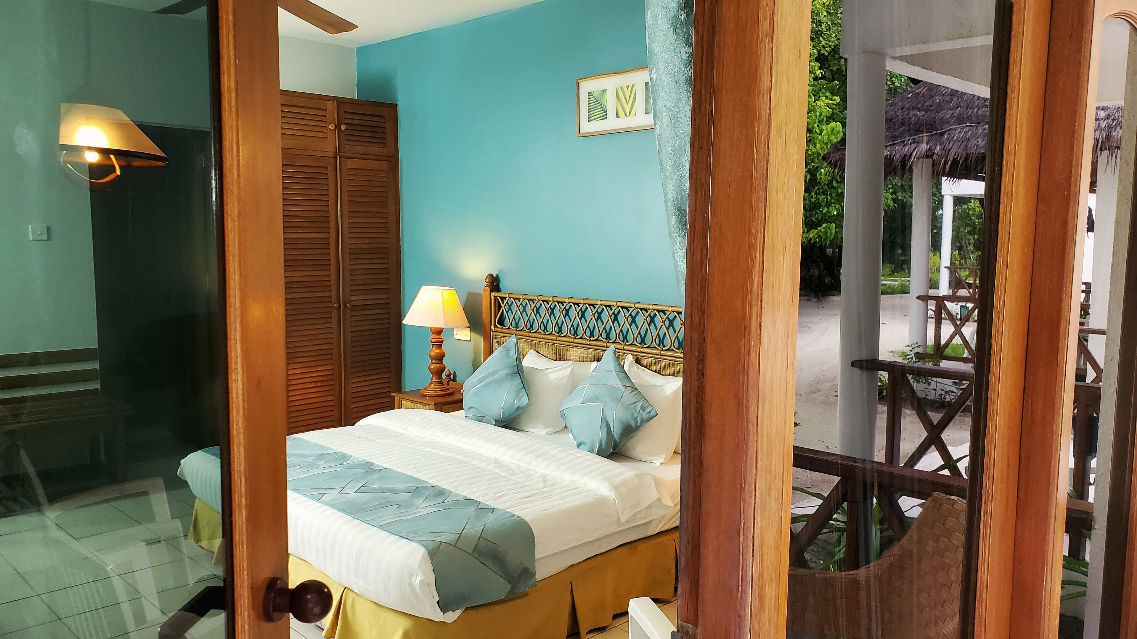 Quarto com cama, cabeceira de madeira e mesa de cabeceira com luminária.