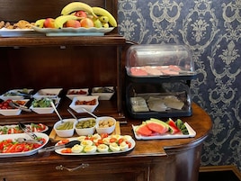 Buffet com diversas opções de comida, incluindo frutas, saladas e carne.