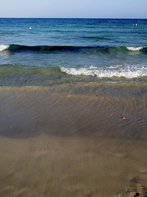 Uma praia com águas cristalinas e ondas.