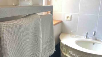 Um banheiro com uma toalha branca pendurada em um porta-toalhas, uma pia e um espelho.