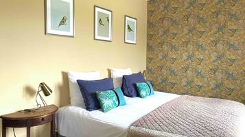 Quarto de hotel com uma cama, uma mesa de cabeceira e três quadros na parede.