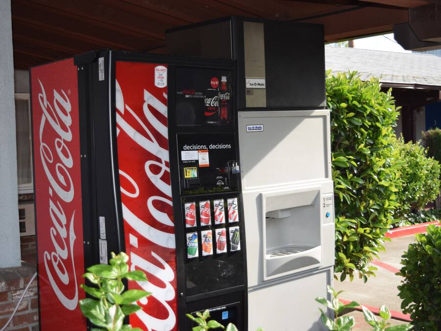 Uma máquina de venda automática de Coca-Cola com visor digital e dispensador de água.